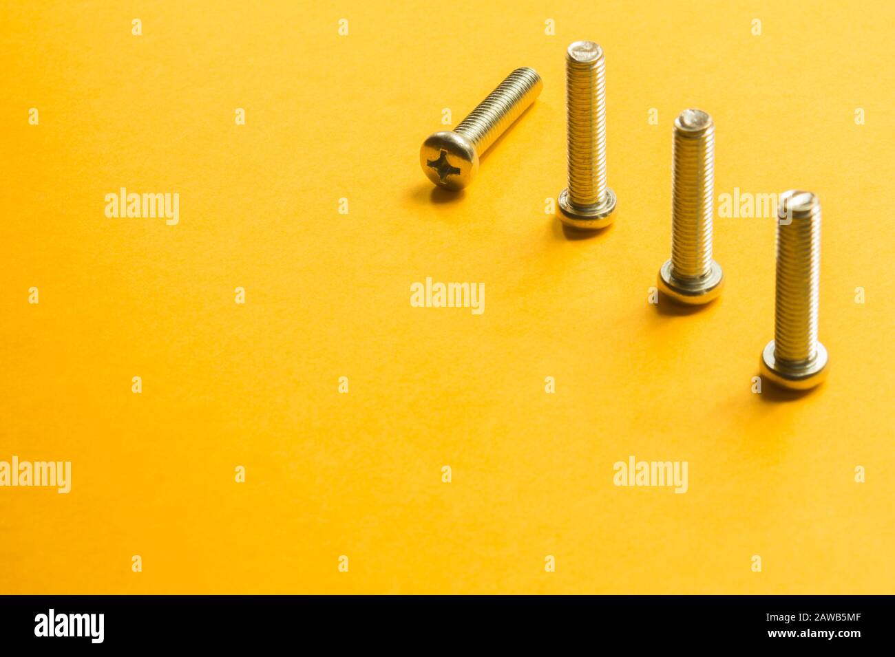 Steel screw on a yellow background. working tools Stock Photo - Alamy