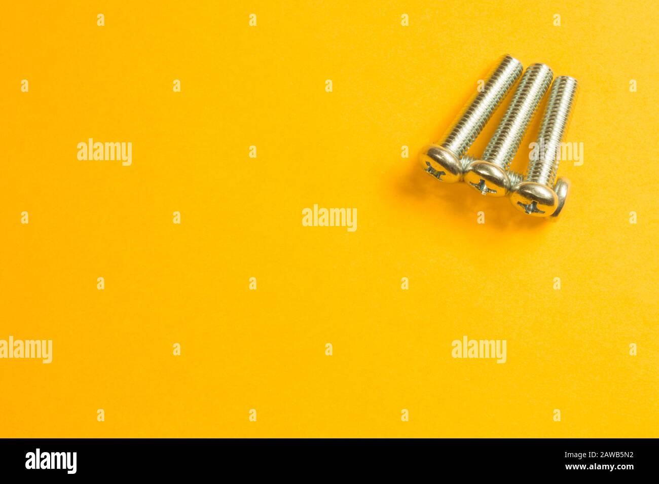 Steel screw on a yellow background. working tools Stock Photo - Alamy