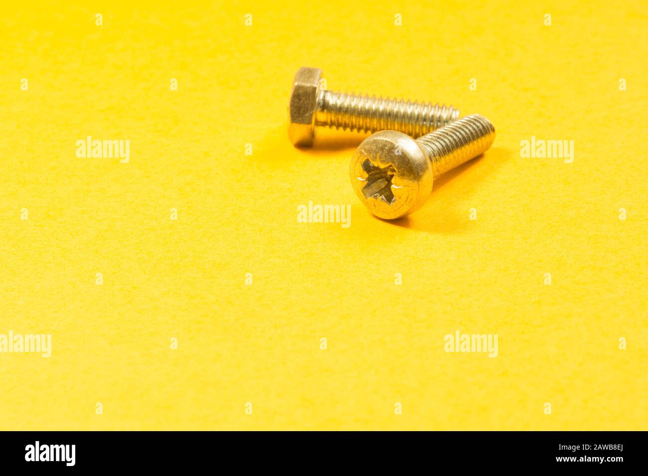 Steel screw on a yellow background. working tools Stock Photo - Alamy