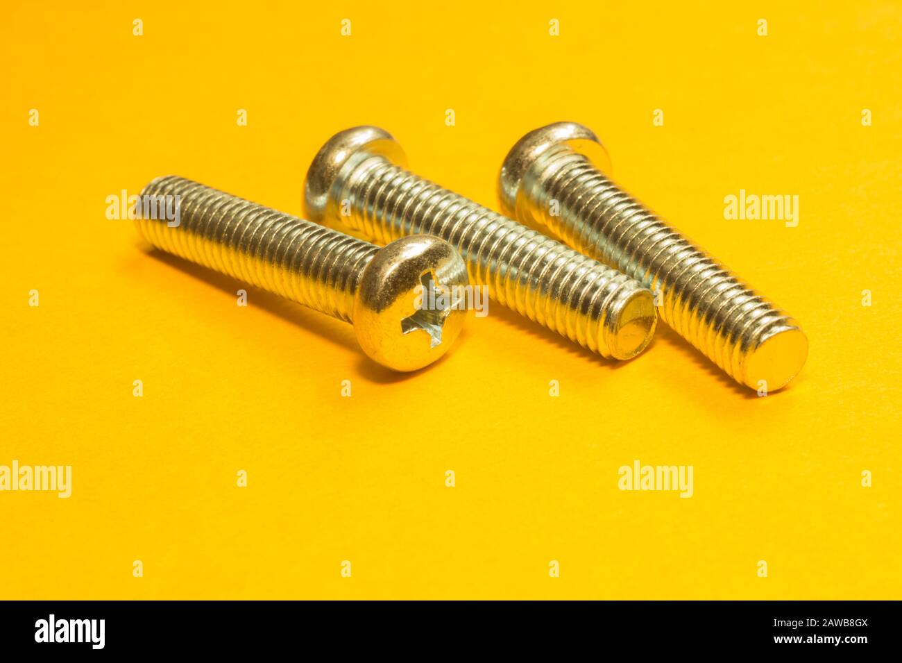 Steel screw on a yellow background. working tools Stock Photo - Alamy