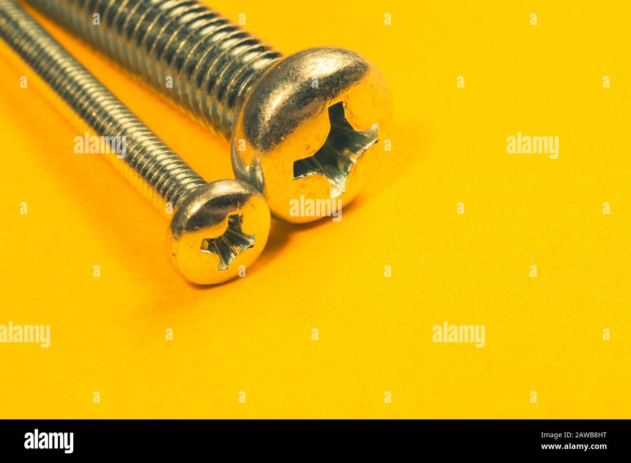 Steel screw on a yellow background. working tools Stock Photo - Alamy