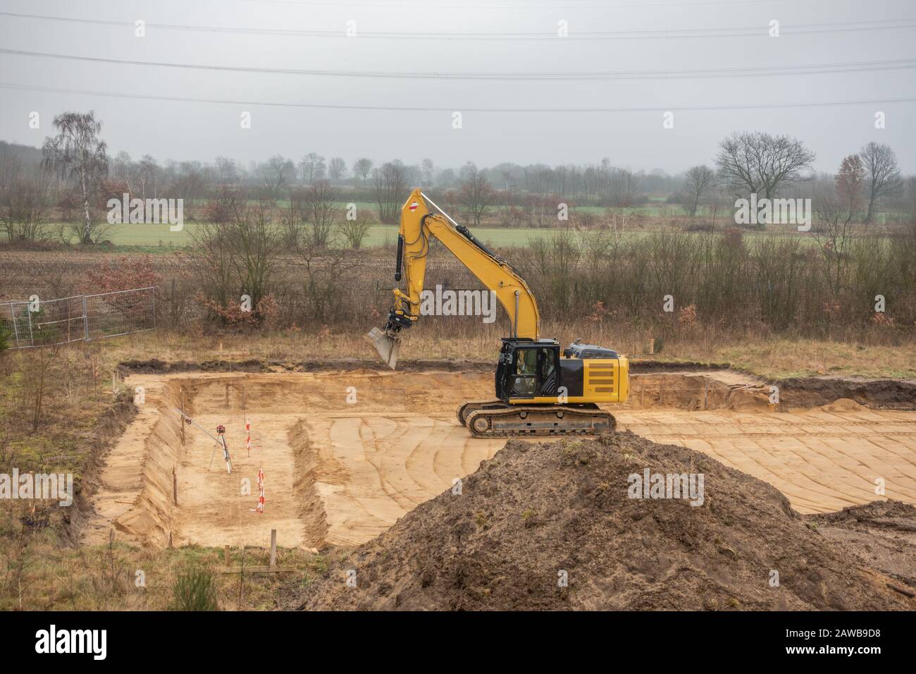on a building site there is a yellow excavator preparing the ground for ...