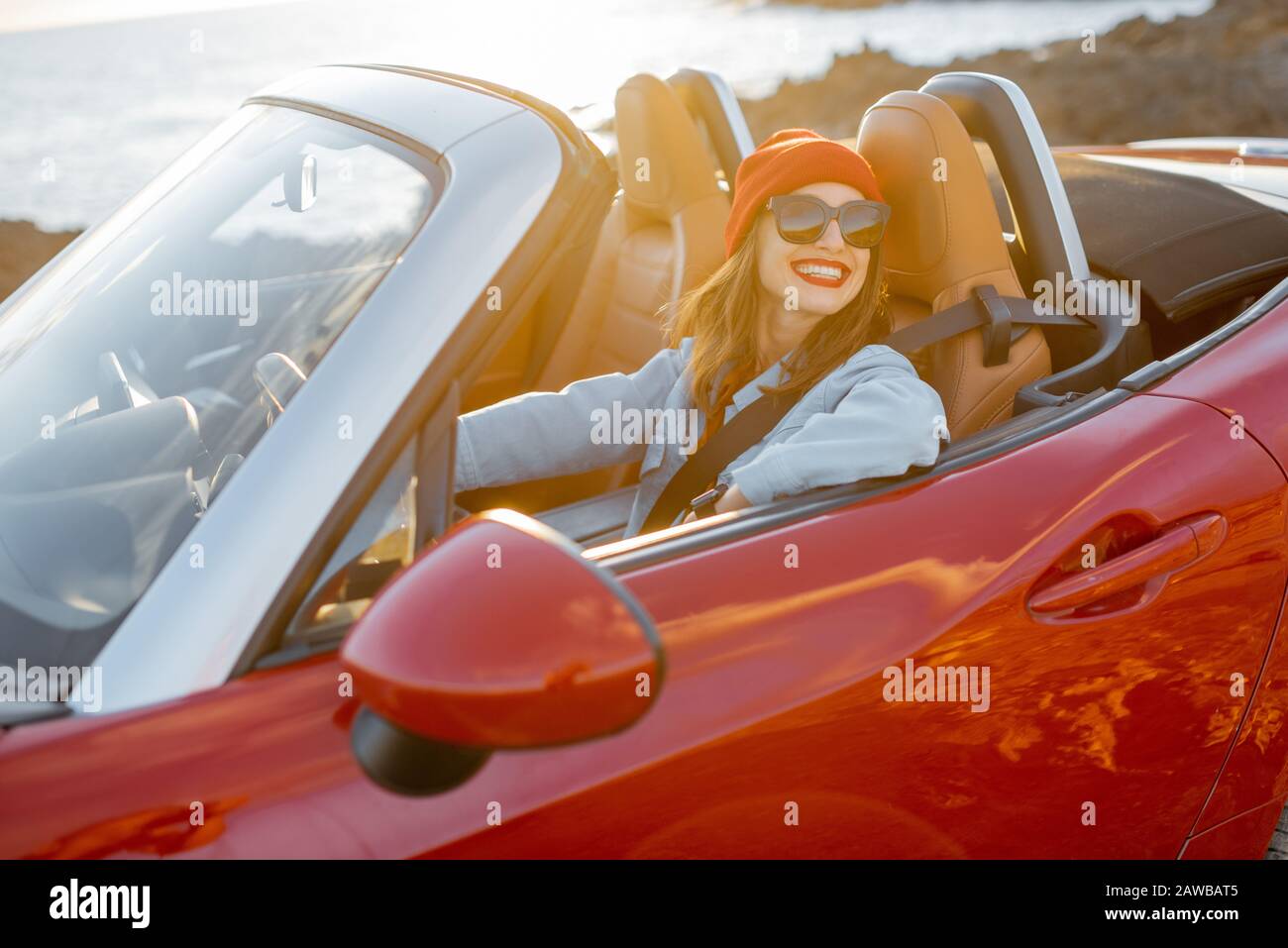 Lifestyle portrait of happy woman in red hat driving convertible car on ...