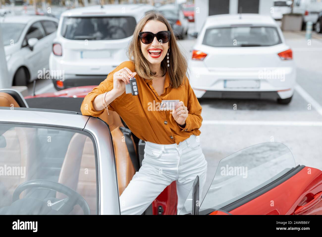 Portrait of a beautiful young woman standing with keys near the red ...