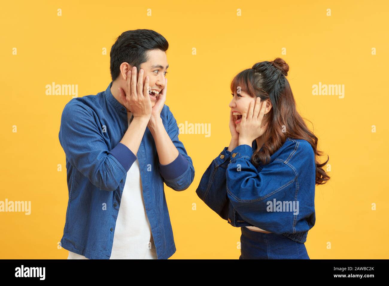 Studio shot of cheerful young people, clasp hands near face, rejoice ...