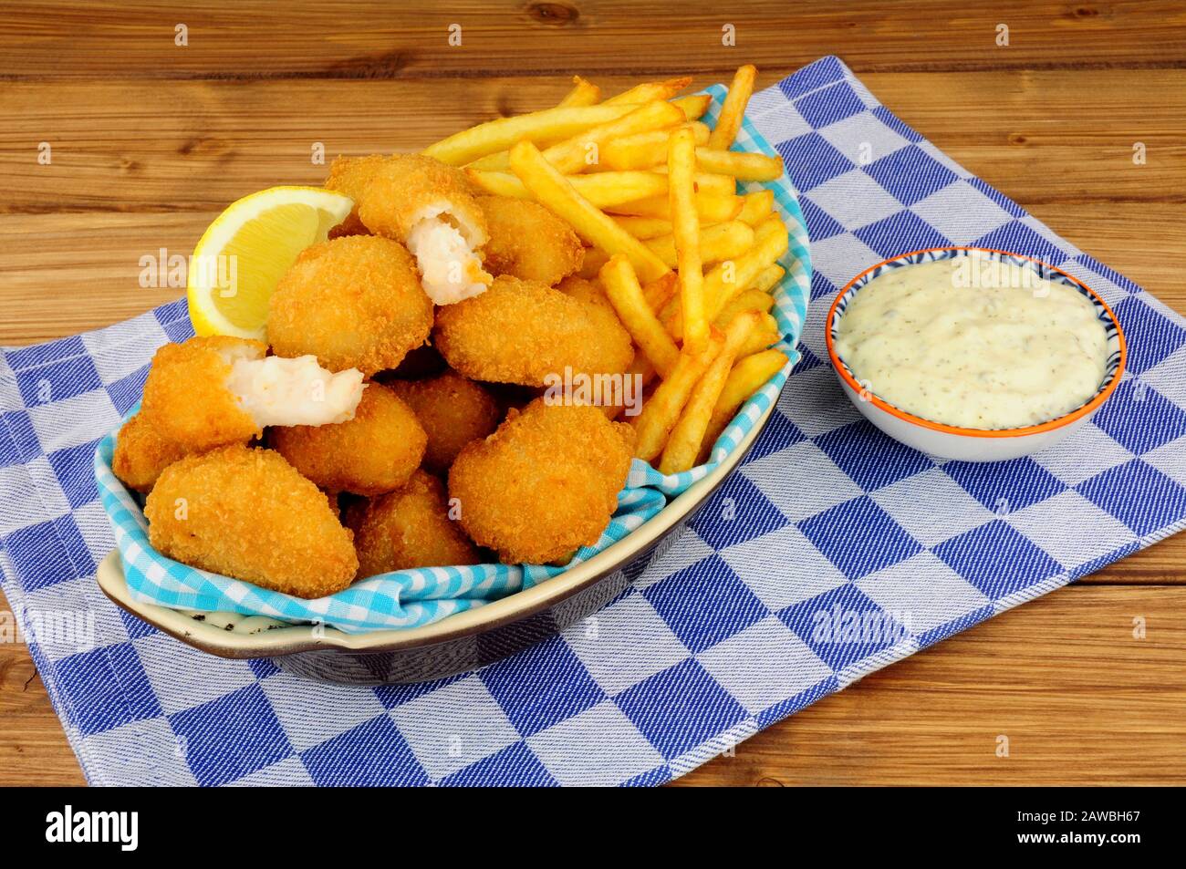 Scampi and French fries meal with tartar sauce on a wooden background ...
