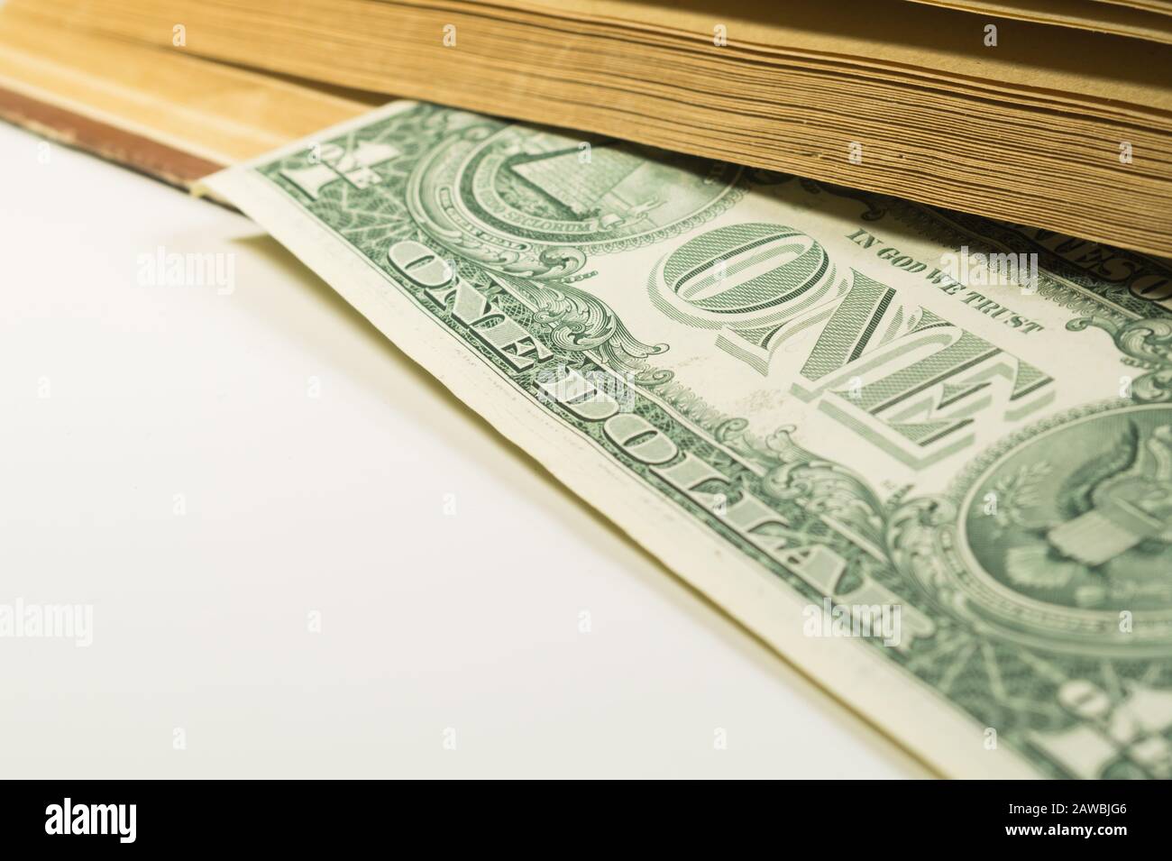 Money in a book. dollar bill used as a bookmark in the book on a white ...
