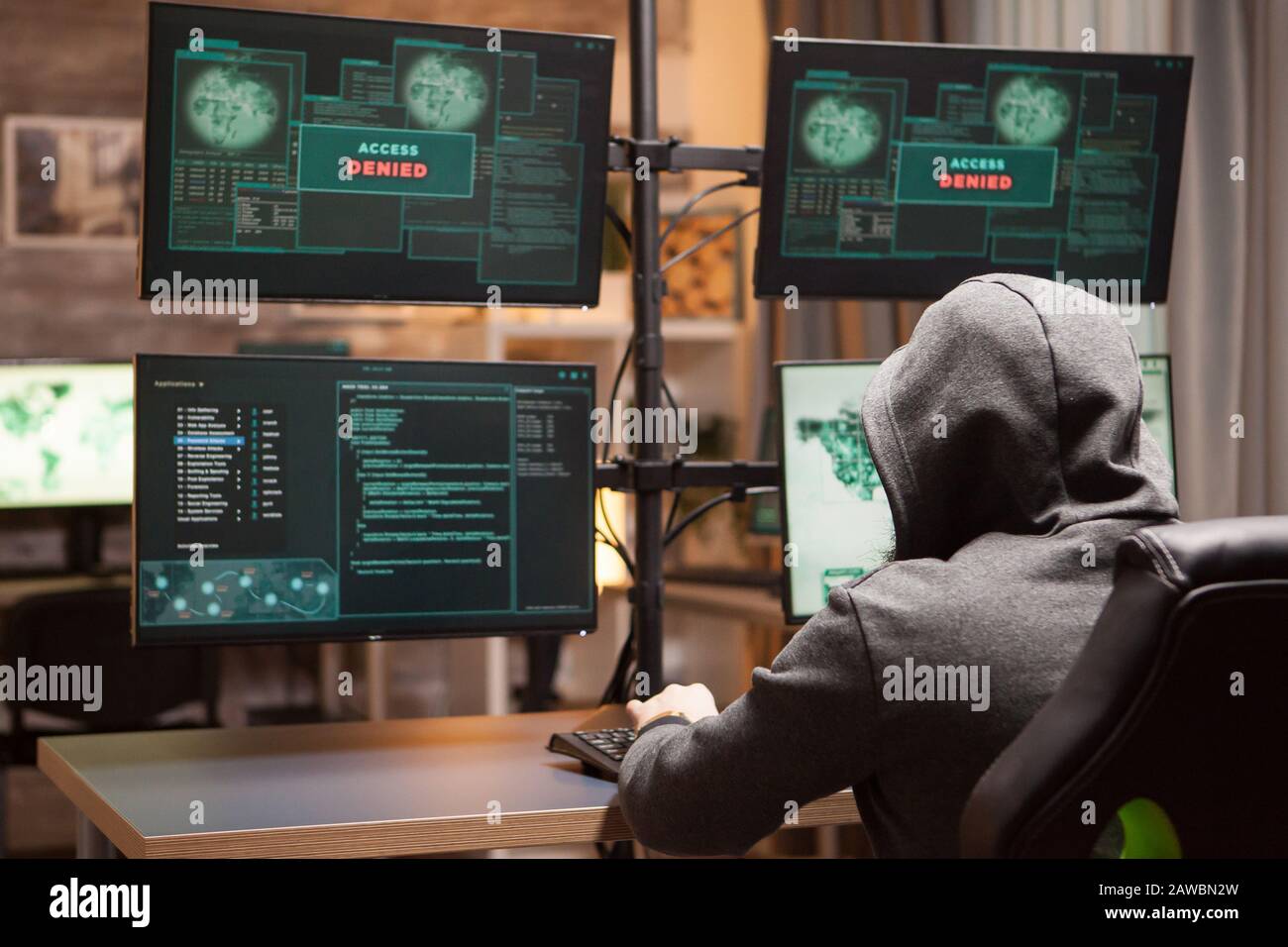 Back view of male hacker wearing hoodie while doing cyberterrorism ...