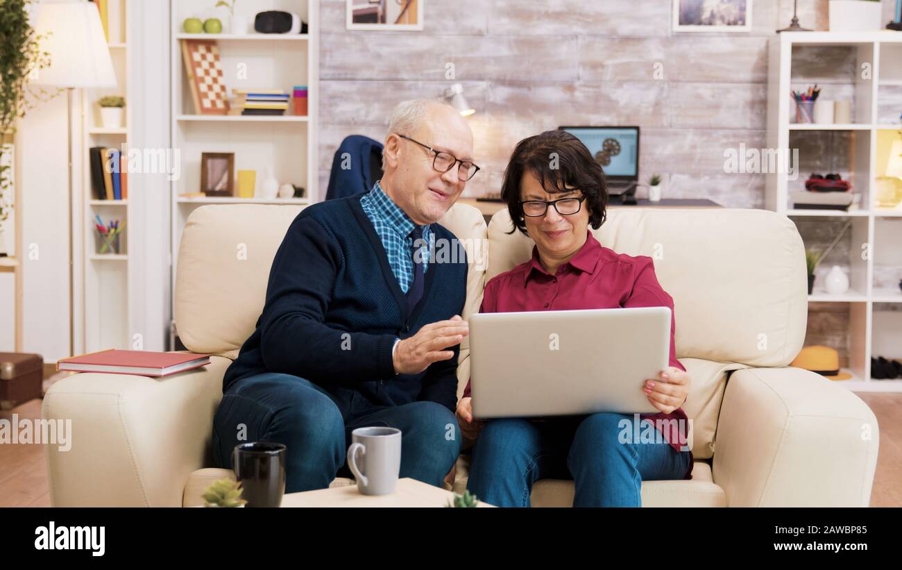 Seniors couple during a video call sitting on the couch in the living ...