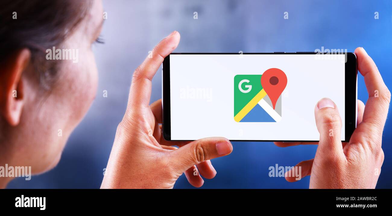 POZNAN, POL - JUL 10, 2019: Woman holding smartphone displaying logo of Google Maps, a web ...