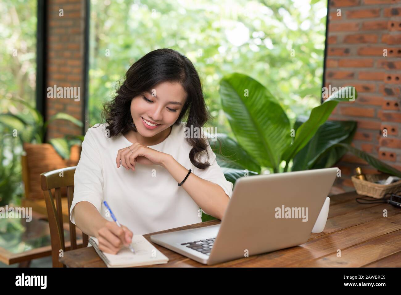 Attractive young Asian writing while using laptop at coffee shop Stock ...