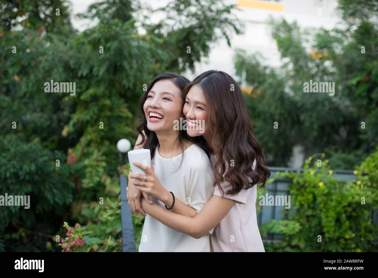 Two young Asian woman hugging in the balcony Stock Photo - Alamy