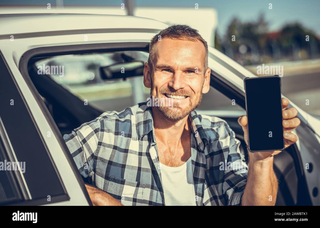 An attractive man in a car shows a smartphone Stock Photo - Alamy