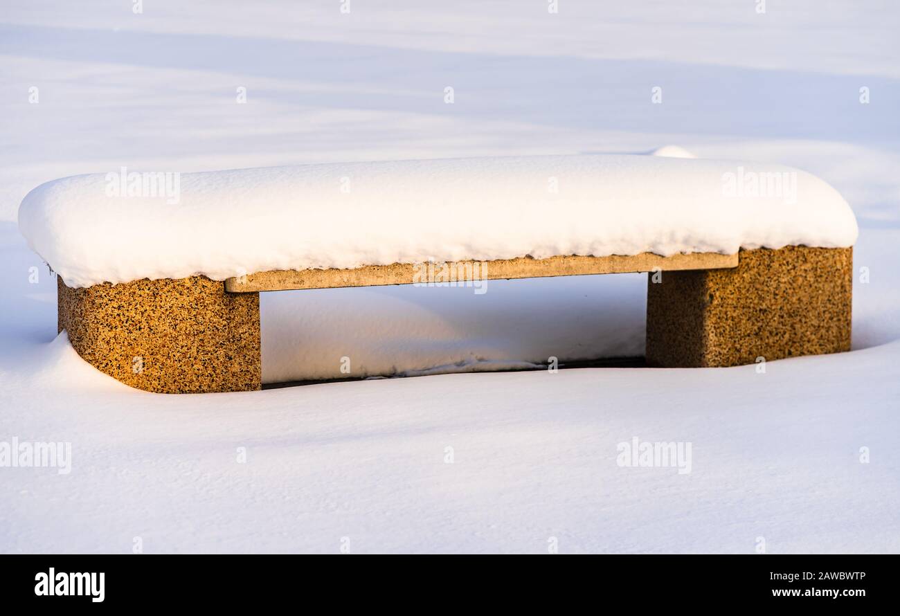 Snow-covered bench in the park. Park bench covered with snow from the ...