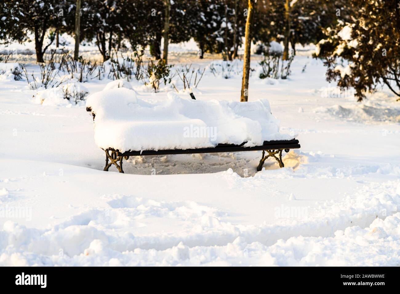 Snow-covered bench in the park. Park bench covered with snow from the ...
