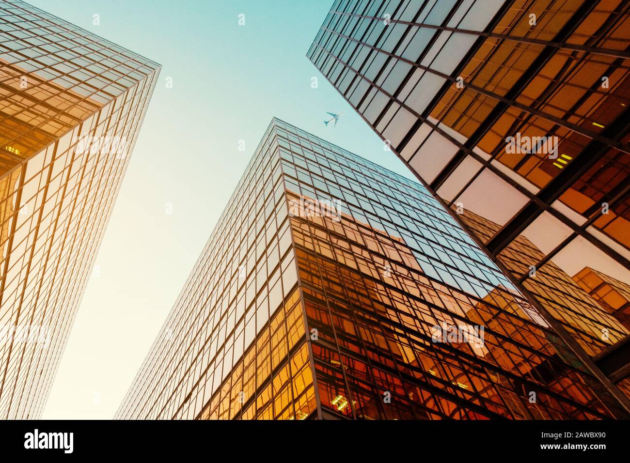 glass facade of gold colored office buildings, sky and airplane Stock ...