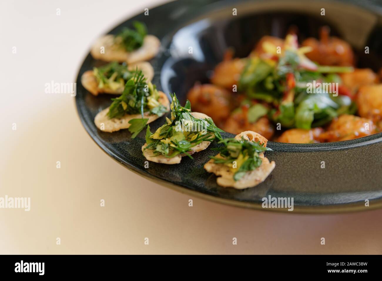 Fried frog legs in black plate, focus on bread chips with herbs Stock ...