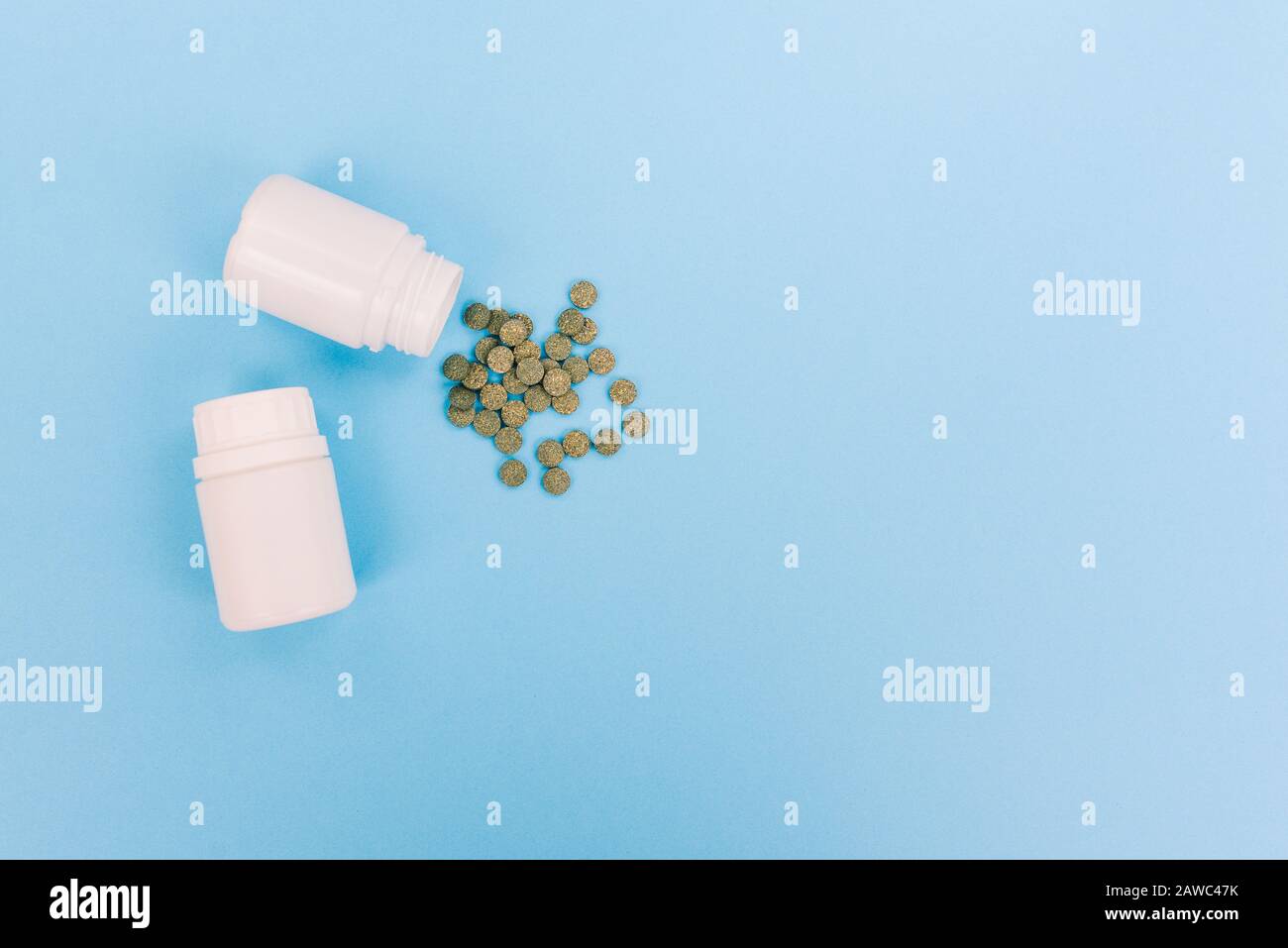 Green scattered tablets. White plastic jars with drugs, vitamins and ...