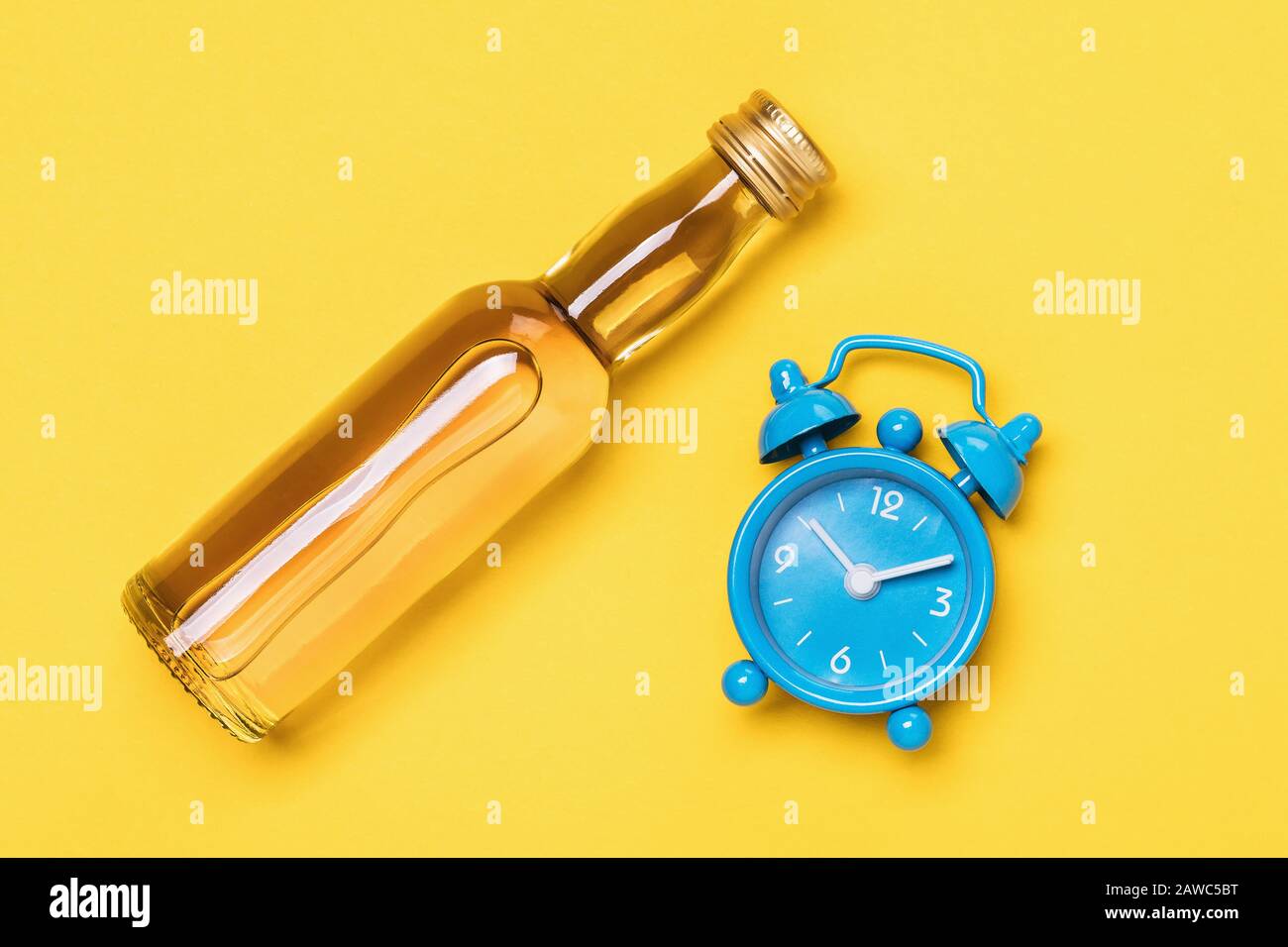 Bottle of whiskey and watch on a yellow background, top view. Concept ...