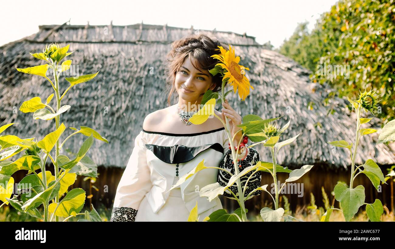 Woman smelling a flower, enjoying nature. On the background of a hut ...