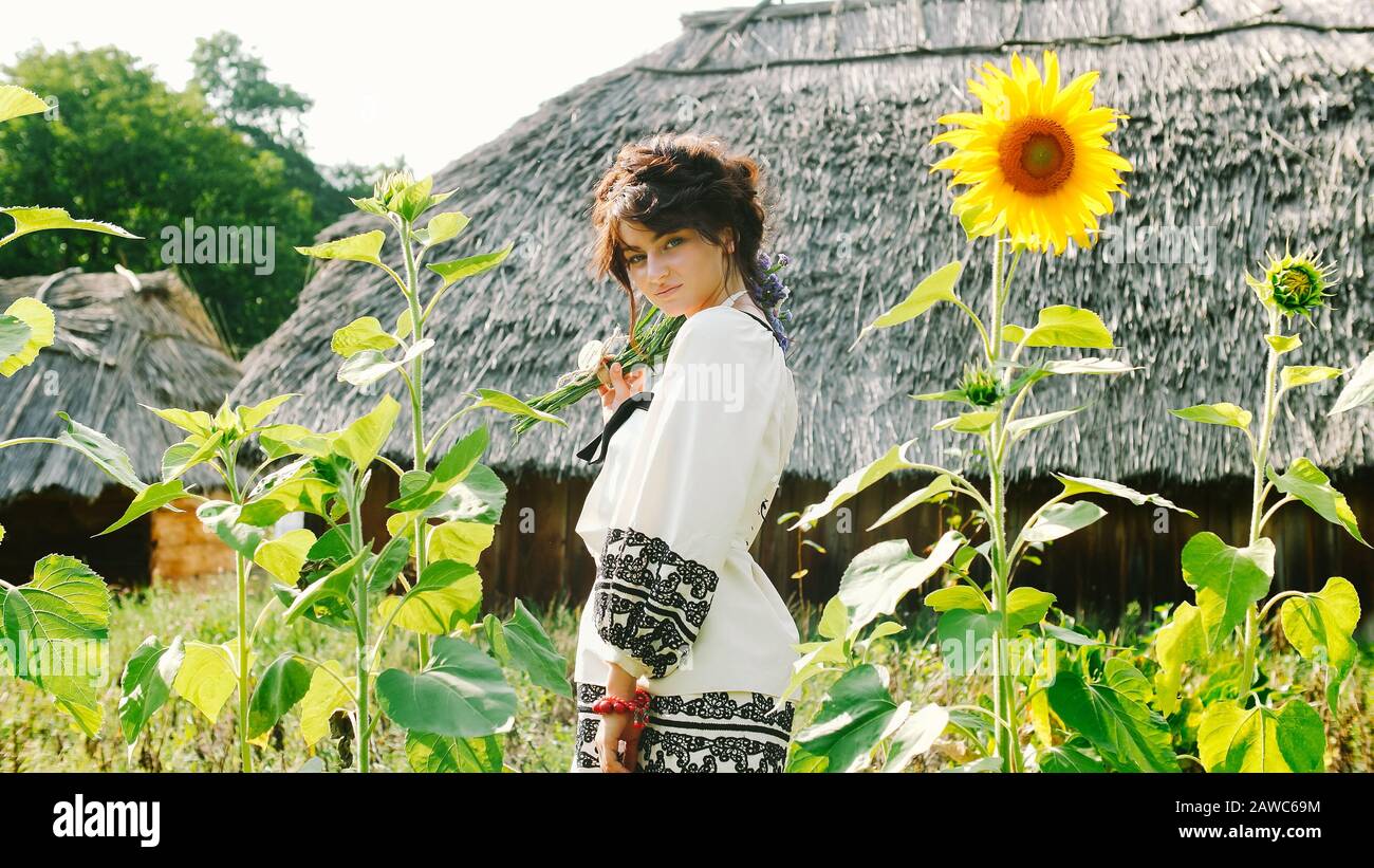 Woman smelling a flower, enjoying nature. On the background of a hut ...