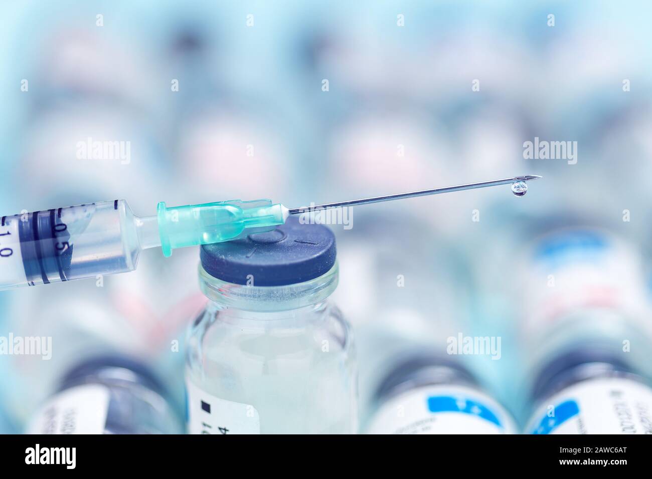 Syringe over medicine bottles on a blue background. Injection needle ...