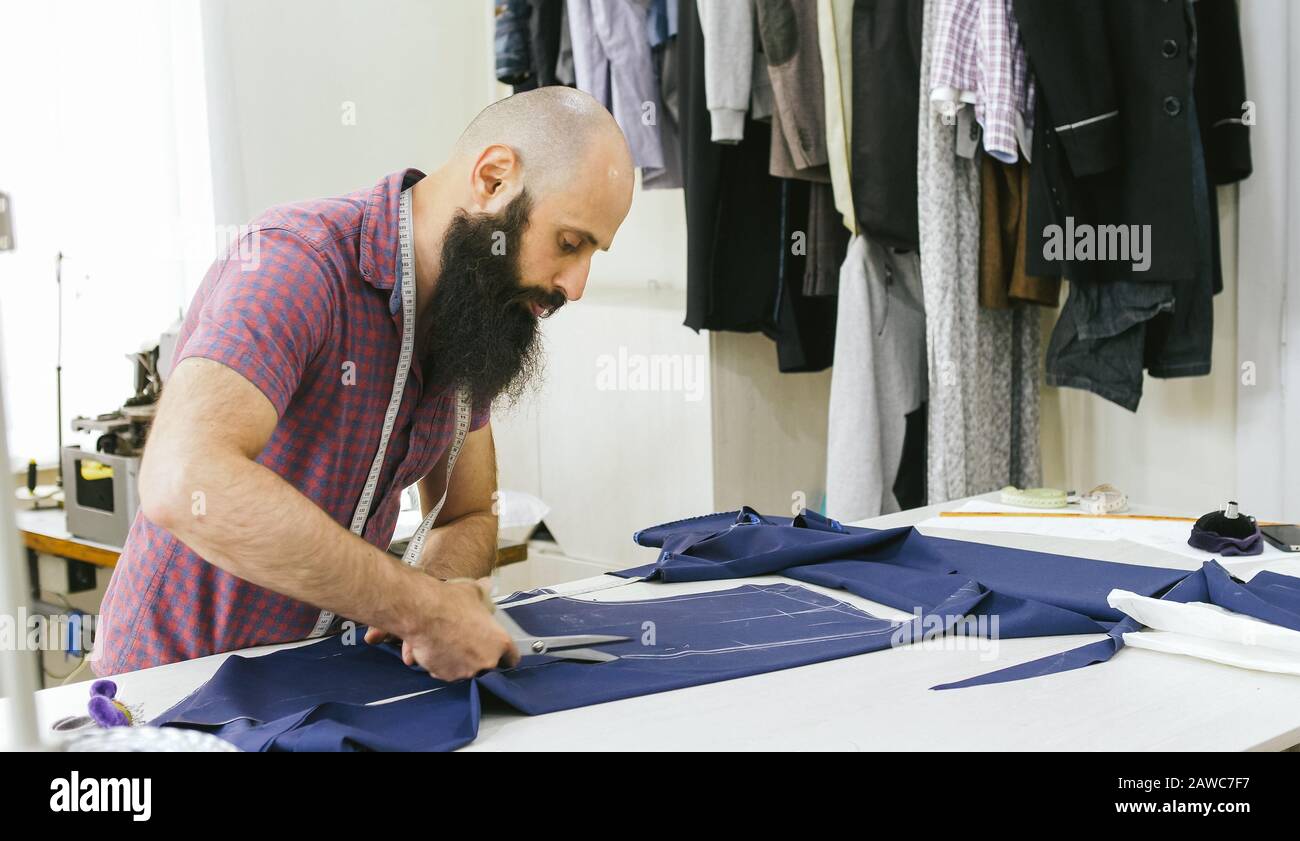 A tailor in a sewing workshop at work. His Studio is Sunny. Colored ...