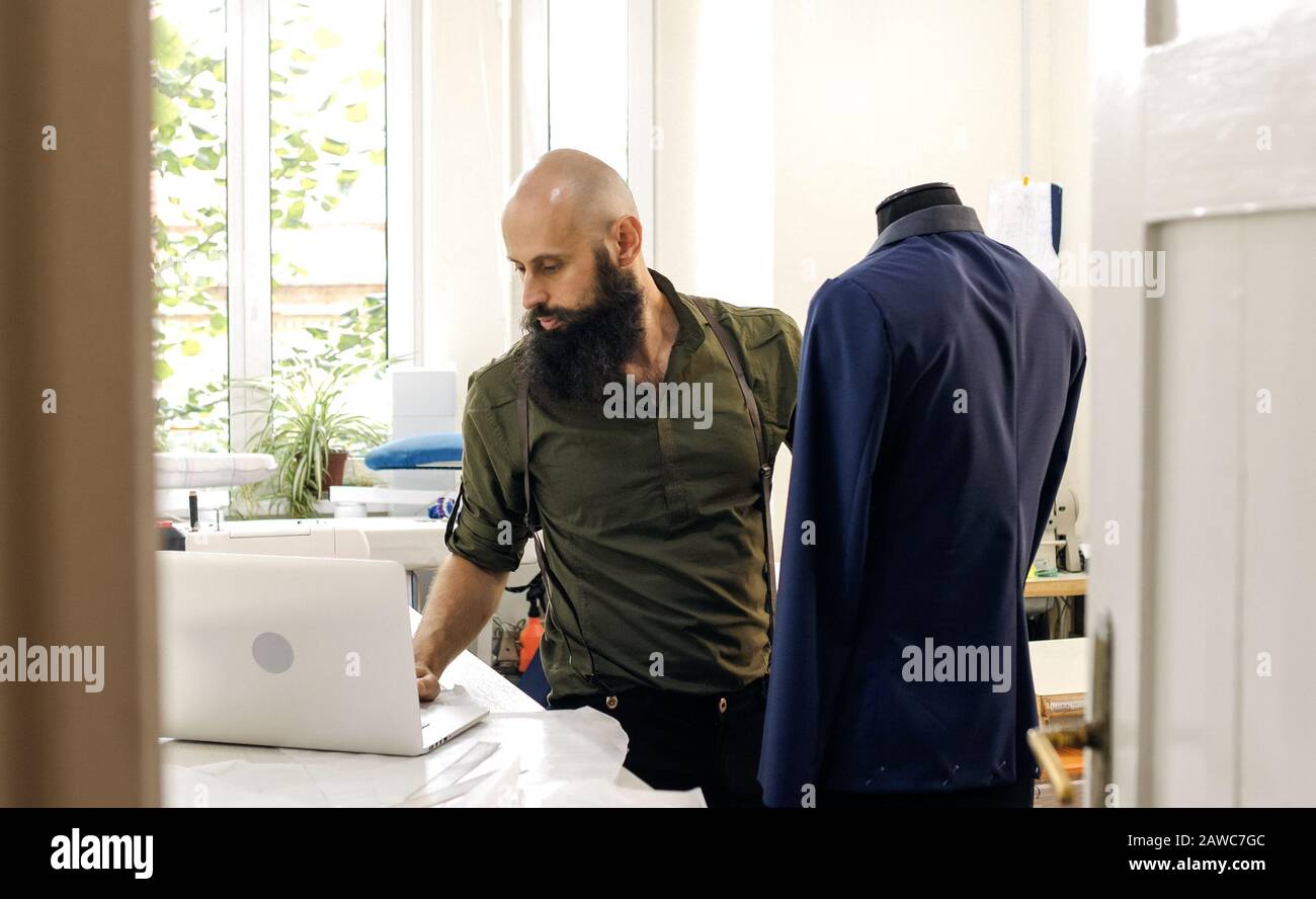 A tailor in a sewing workshop at work. His Studio is Sunny. Colored ...