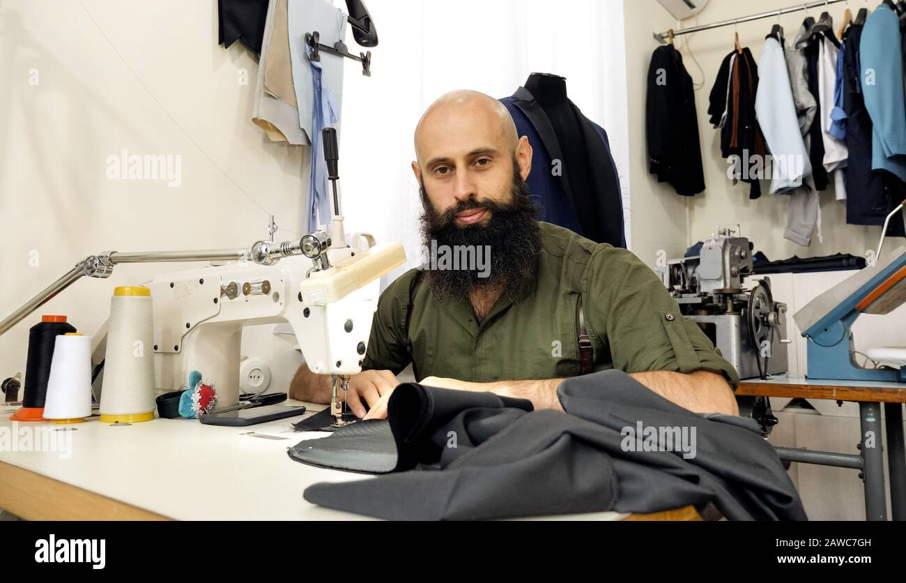 A tailor in a sewing workshop at work. His Studio is Sunny. Colored ...