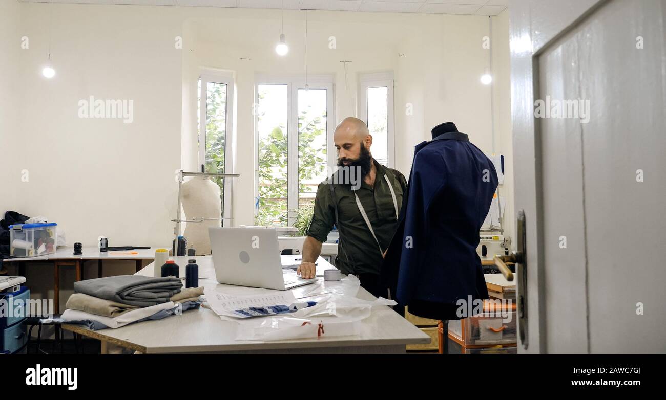 A tailor in a sewing workshop at work. His Studio is Sunny. Colored ...