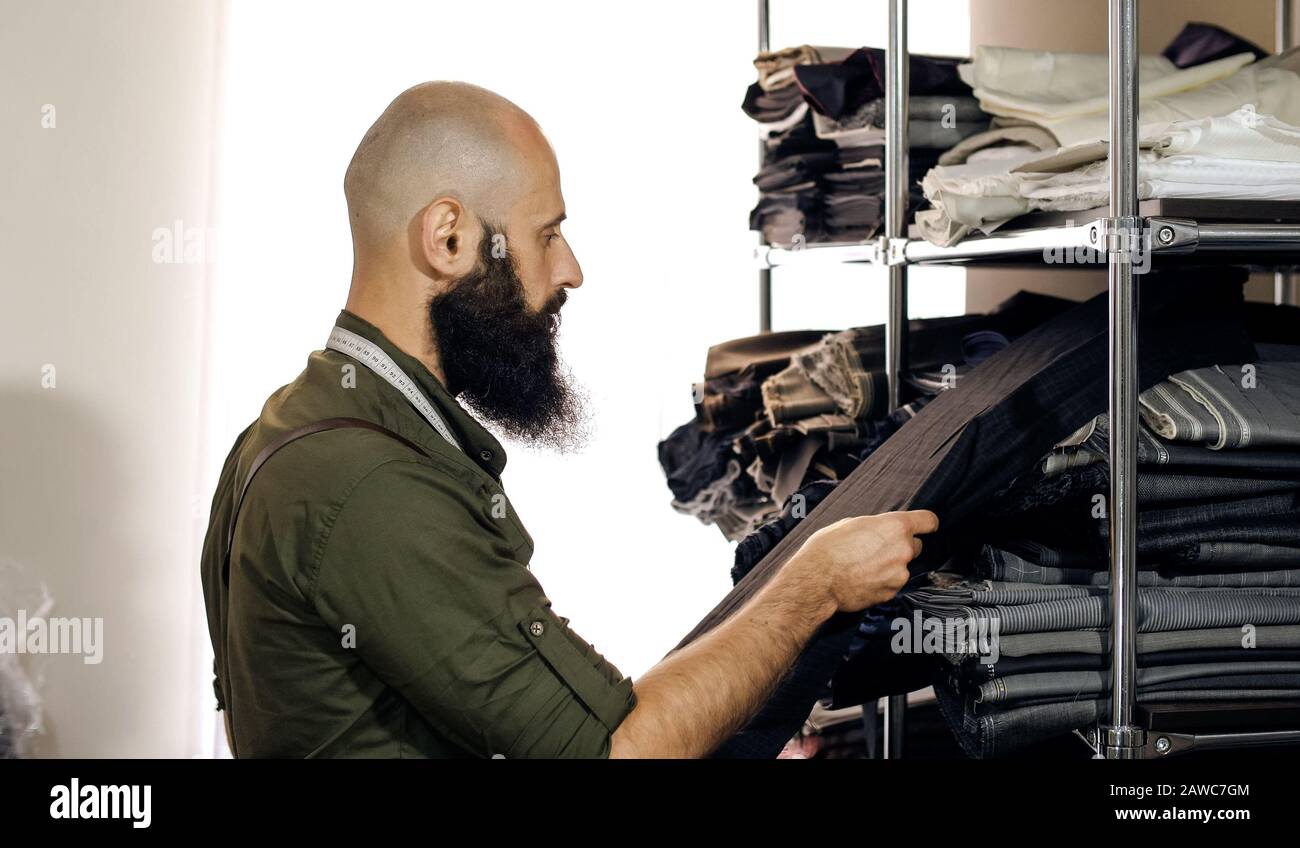 A tailor in a sewing workshop at work. His Studio is Sunny. Colored ...