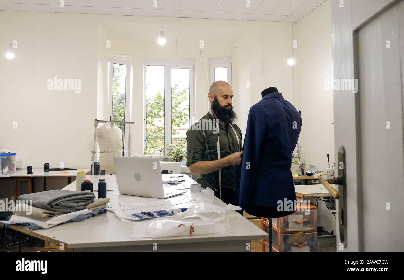 A tailor in a sewing workshop at work. His Studio is Sunny. Colored ...