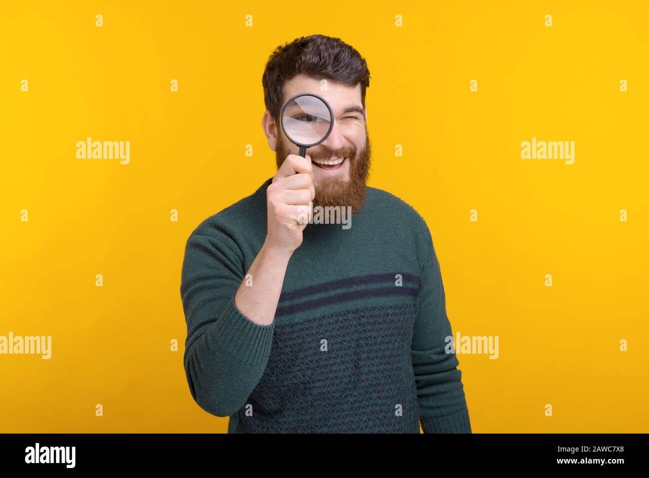 man looking through magnifying glass while standing over yellow ...