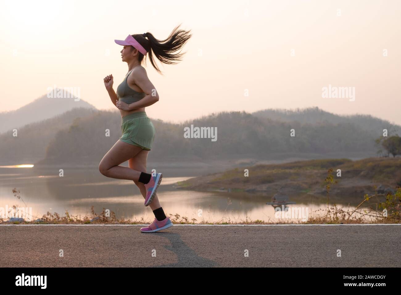 Photo side view Asia young woman runner running on asphalt road at ...