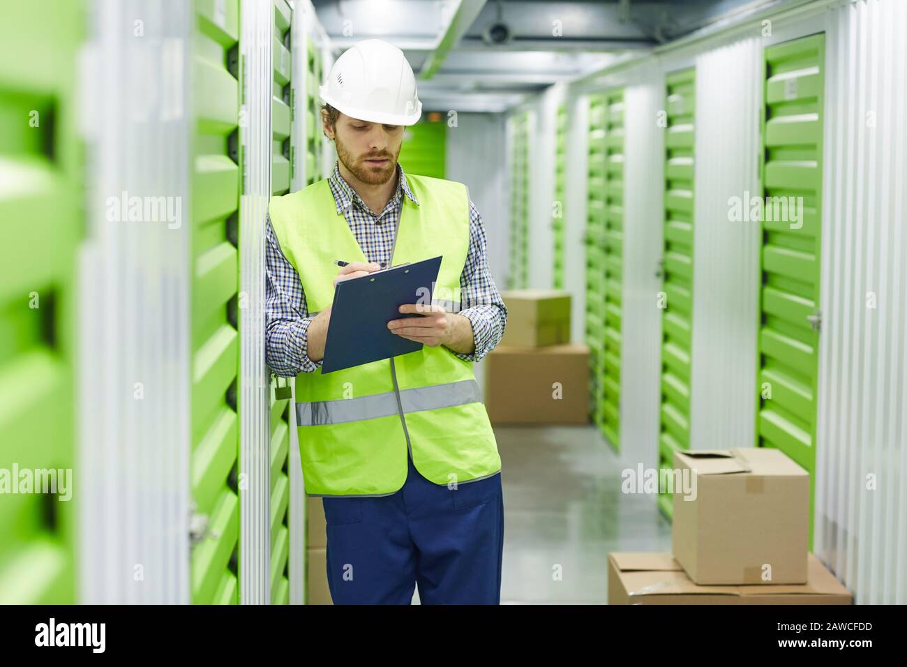 Serious manual worker concentrating on his work in storage room he ...