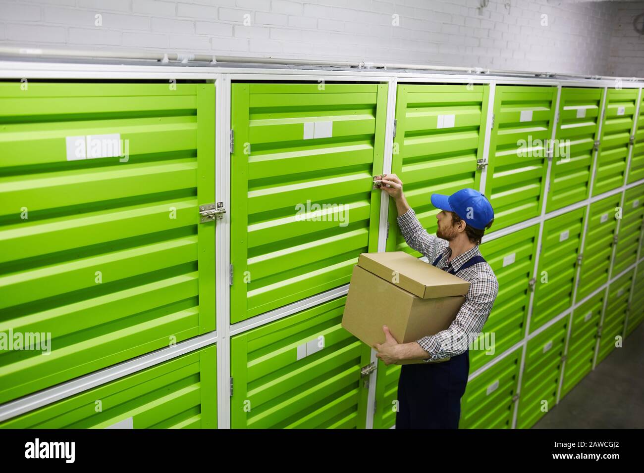 Worker in overalls opening the green door of boxes to put parcel inside ...