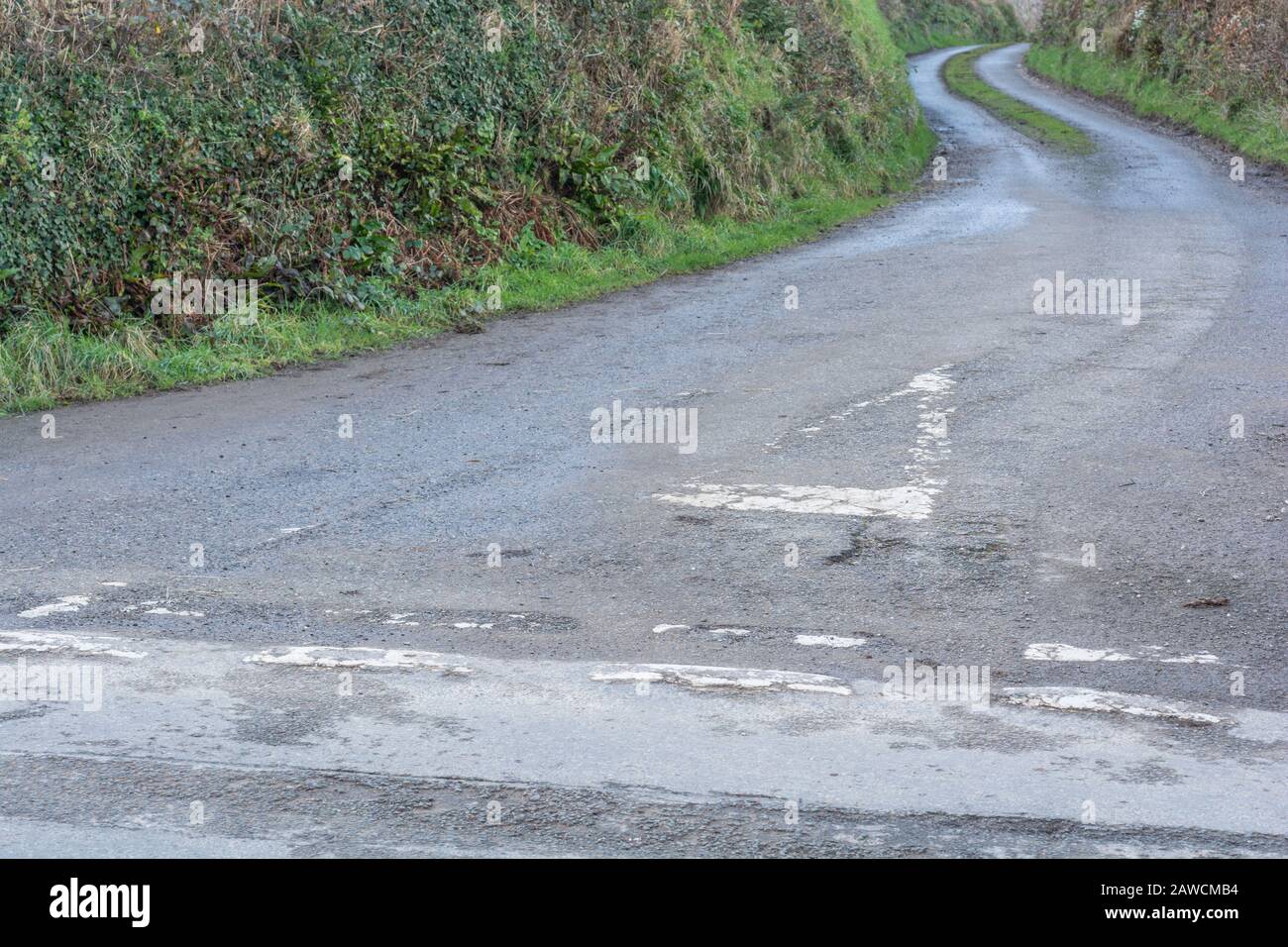 Rural road with faded Give Way junction markings with road receding ...