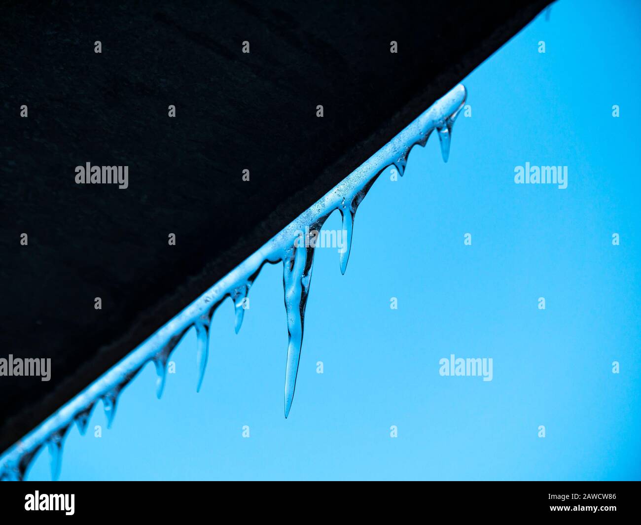 A frozen icicle of ice against a blue sky. Winter. Background image ...