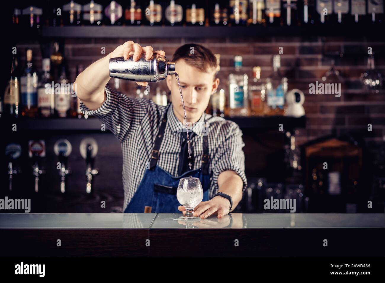 Expert barman making cocktail with shaker in martini glass, red. Dark ... Expert barman making cocktail with shaker in martini glass, red. Dark ...
