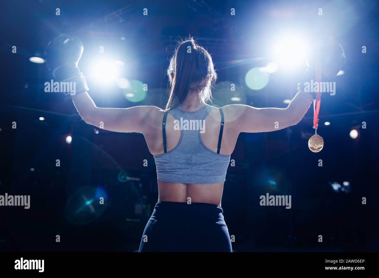 Winner Young female boxer athlete holds gold medal in her hand on dark ...