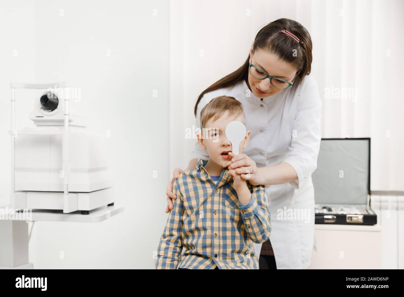 Small serious boy sitting on chair office of vision test. doctor picks ...