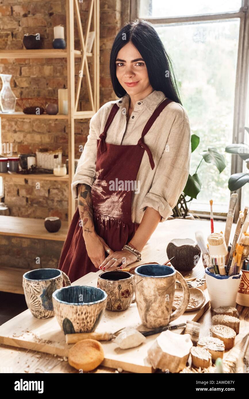 Craftsperson Concept. Young woman making pottery indoors standing near ...