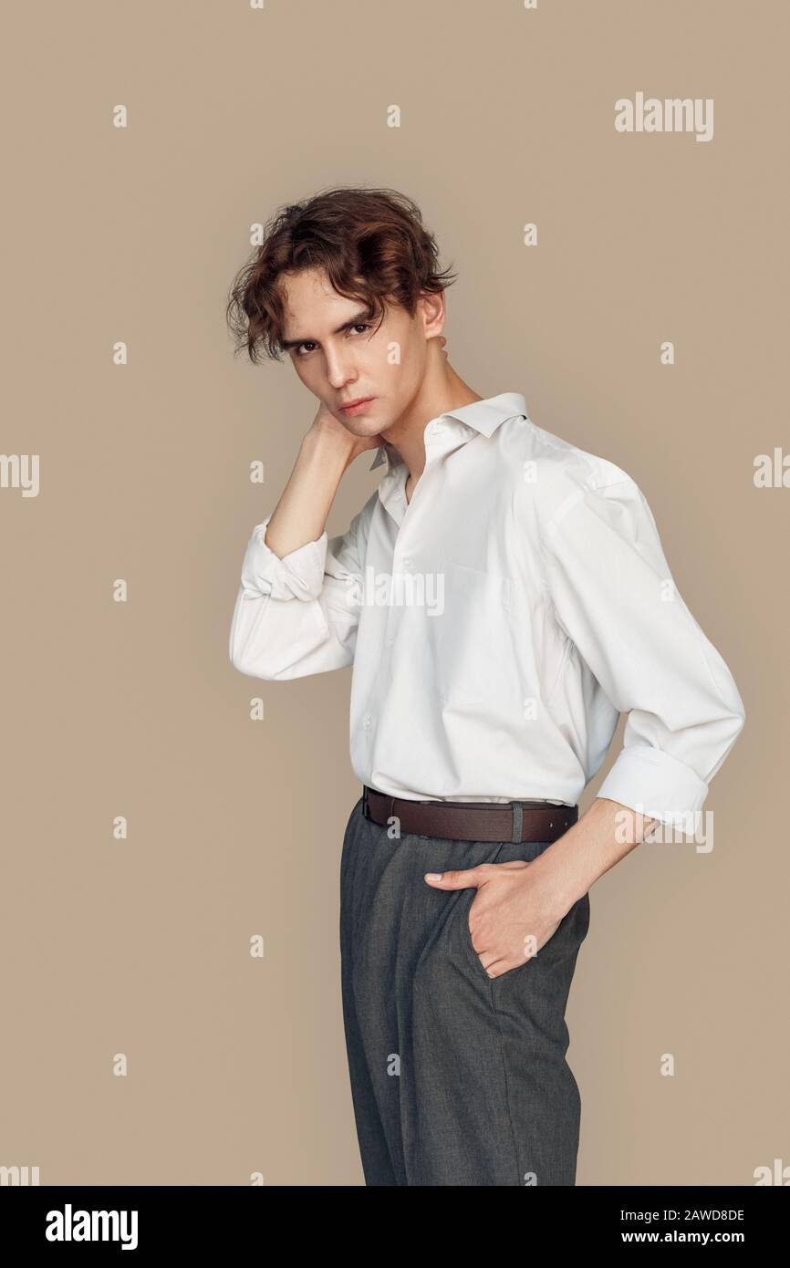 Freestyle. Man in formal wear standing isolated on gray hand in pocket ...