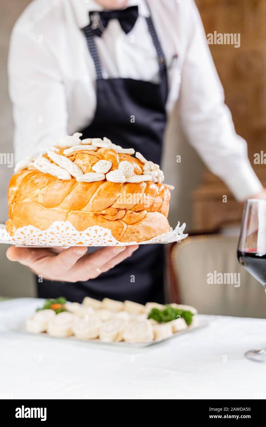 Close up of waiter hand holding traditional orthodox bread next to wine ...