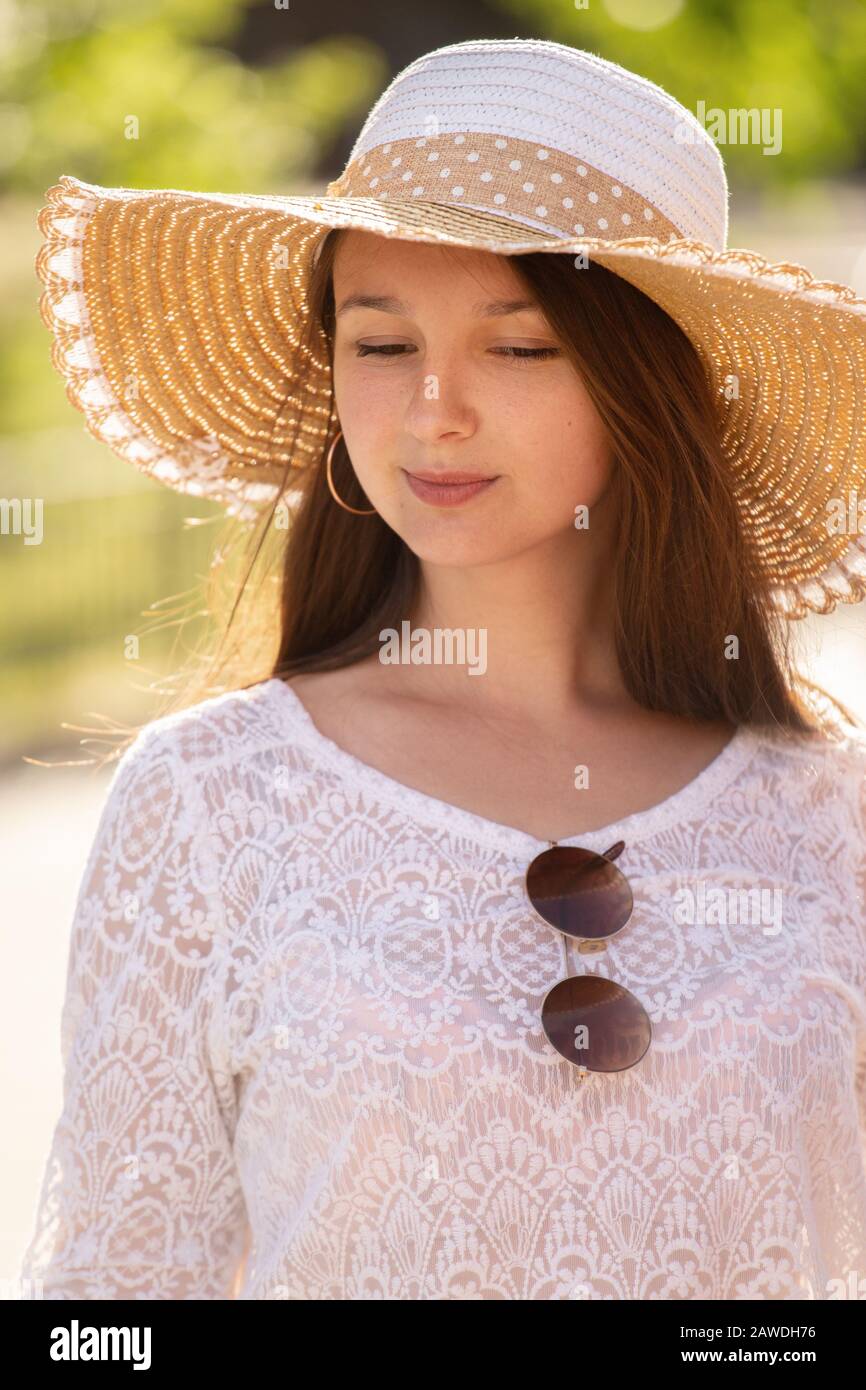 pretty girl in sun hat in sun light looking down, laughing toned image ...