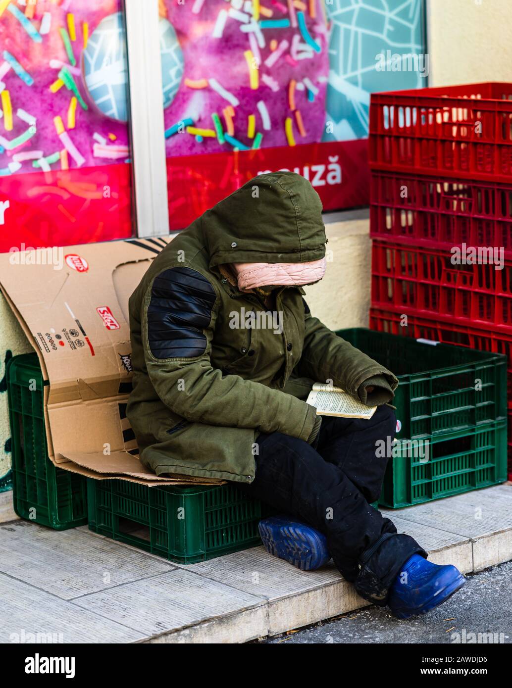 Homeless reading a book in front of a store in the winter, Bucharest ...