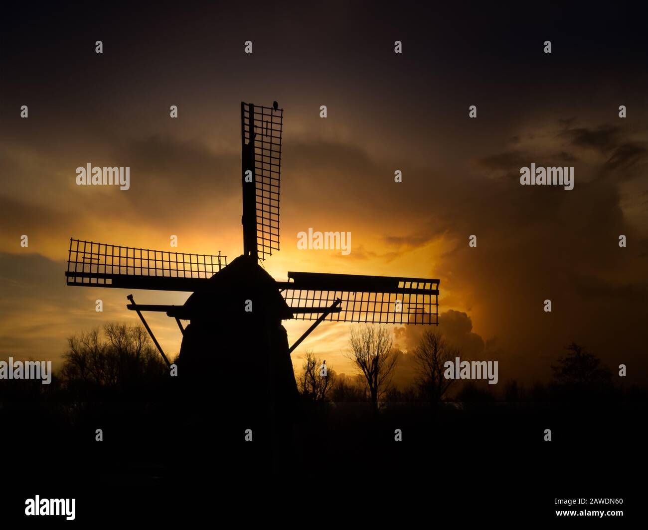 Dutch windmill silhouette with dark, cloudy, high contract sky; sunrise ...