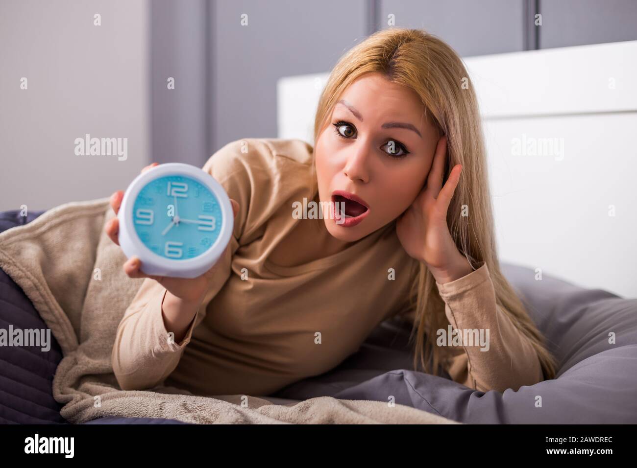 Terrified woman holding alarm clock Stock Photo - Alamy