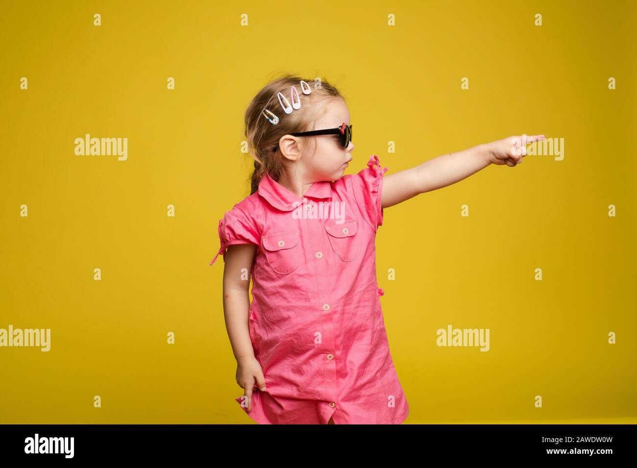 Little girl in dress and sunglasses indicating the direction Stock ...