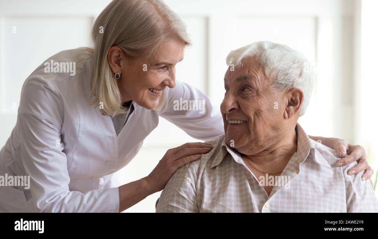 Positive female nurse taking care of senior male patient Stock Photo ...